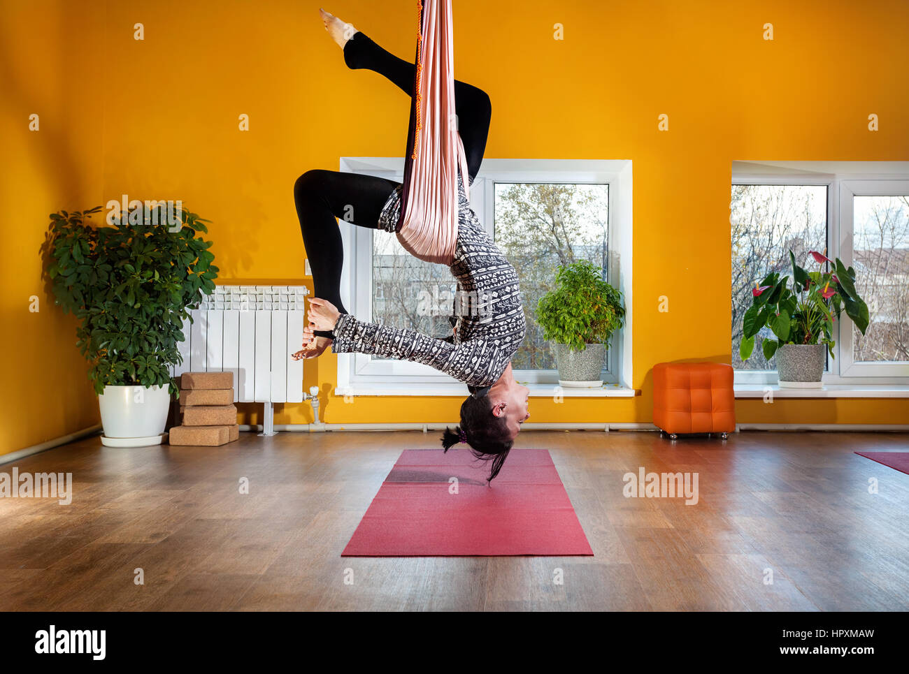 Young woman doing antigravity yoga inverted position at wellness studio ...