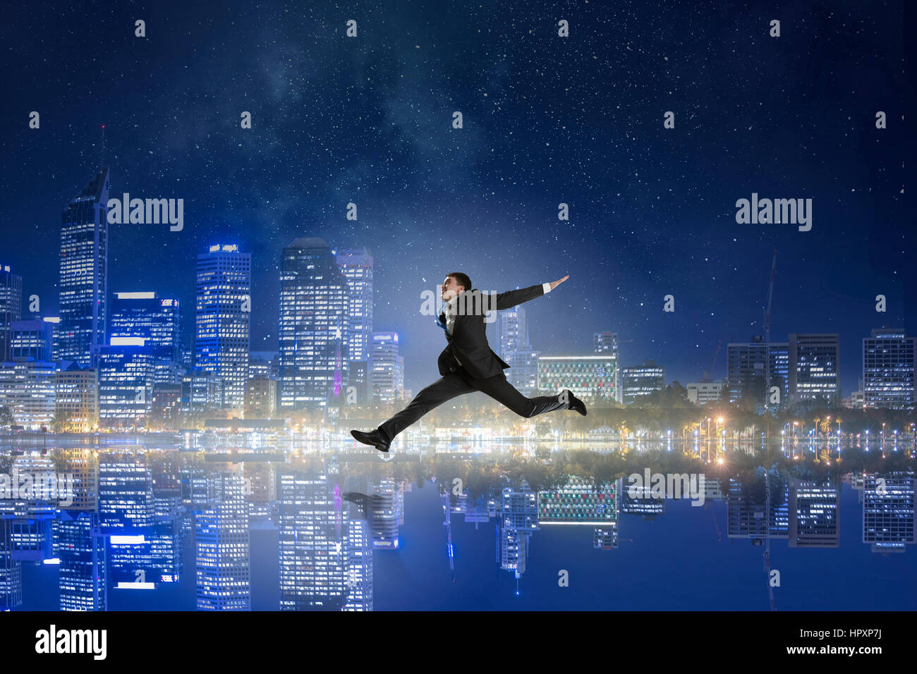 Cheerful businessman in suit jumping on night city background Stock ...