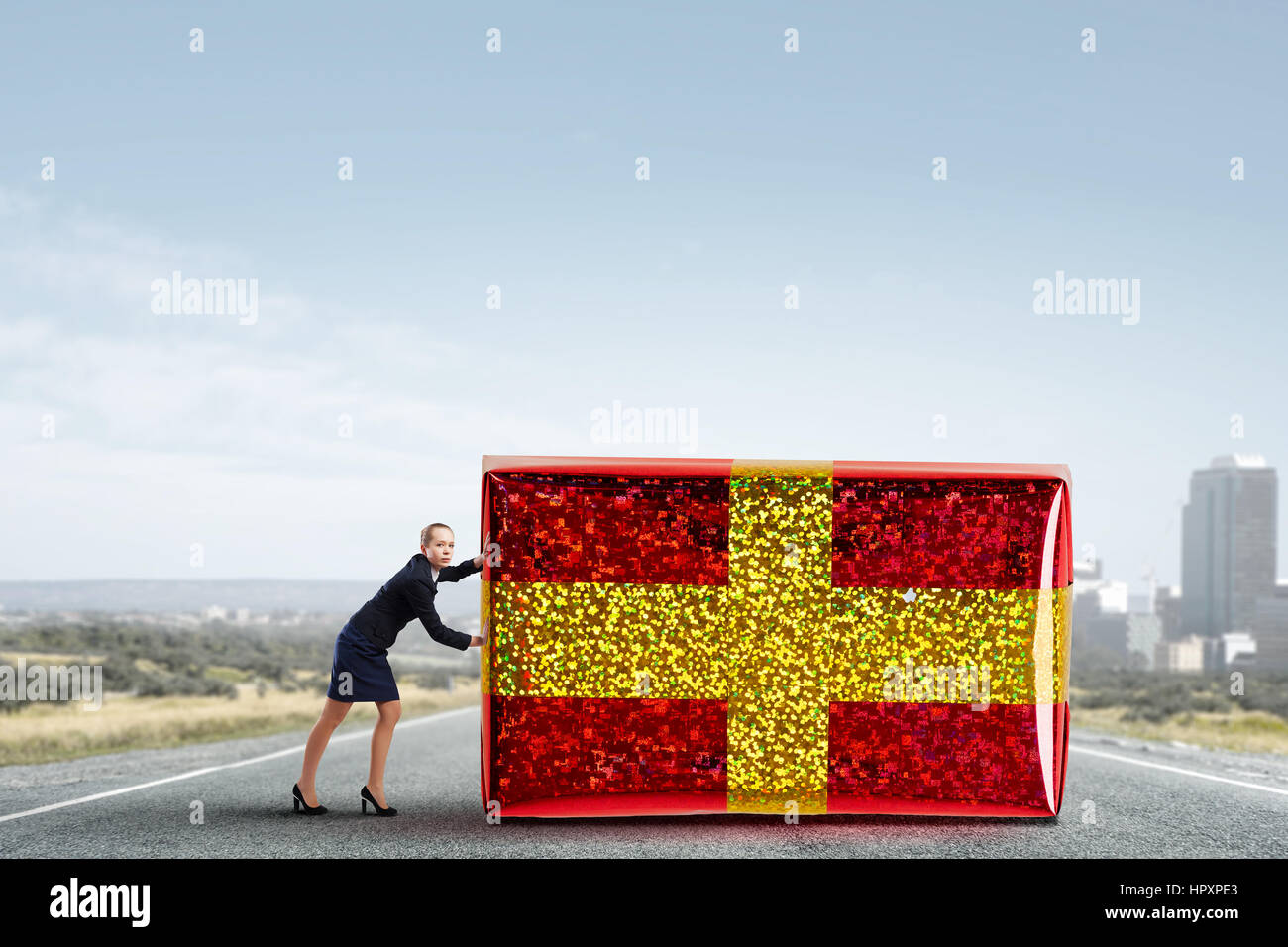Young woman outdoor pushing big gift box Stock Photo - Alamy