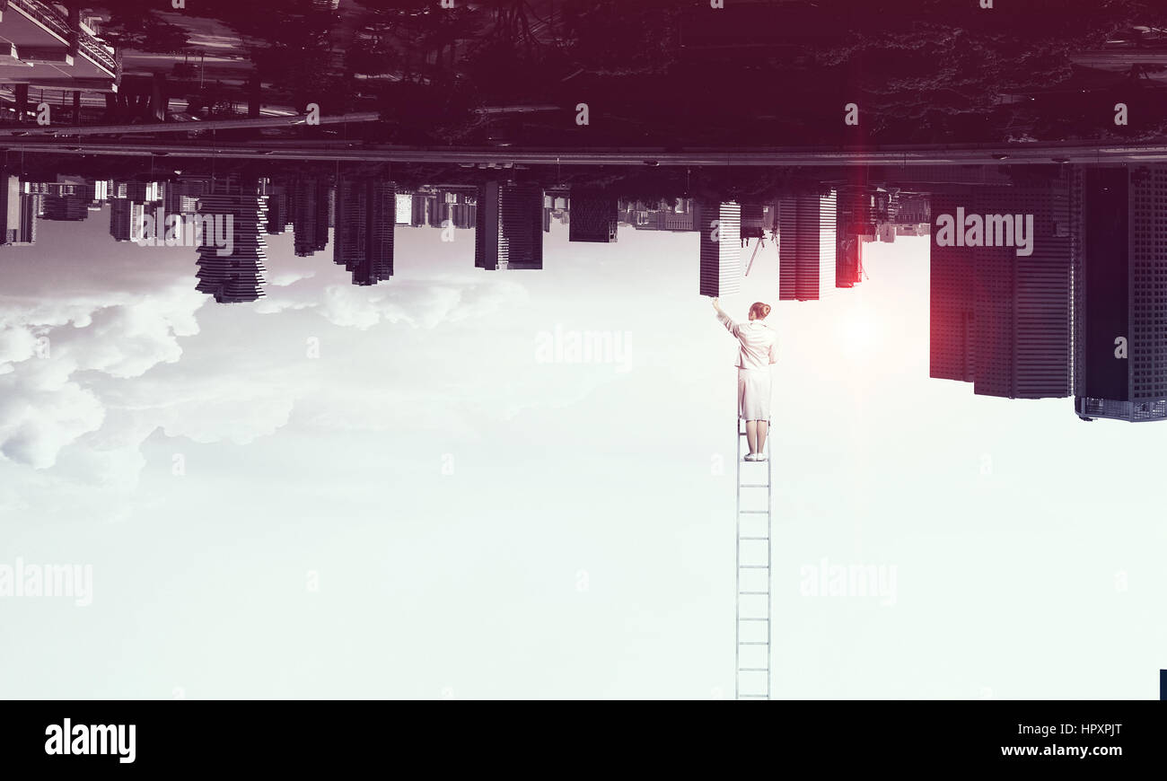 Businesswoman climbing ladder reaching reflection of modern city in sky ...
