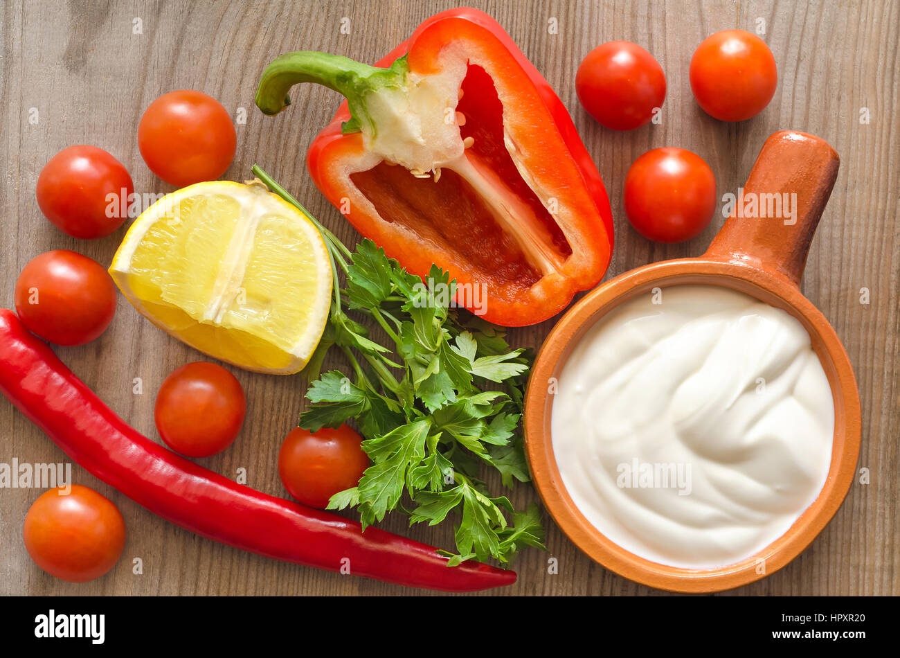 Ceramic dishes with sour cream, and ingredients for salad on an old ...