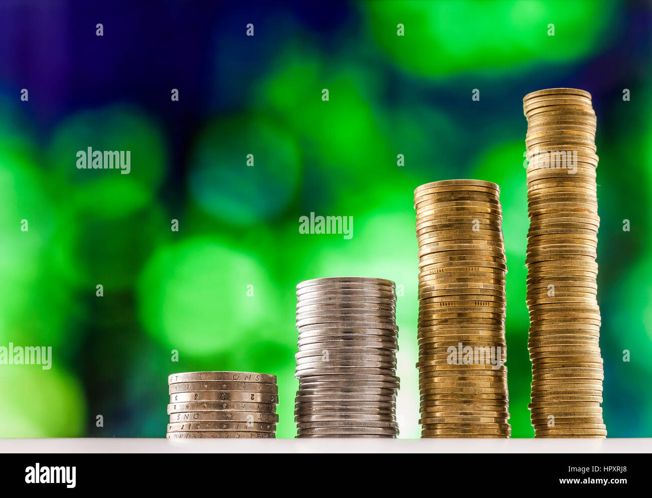 Growing coins stacks with green and blue sparkling bokeh background. Financial growth, saving ...