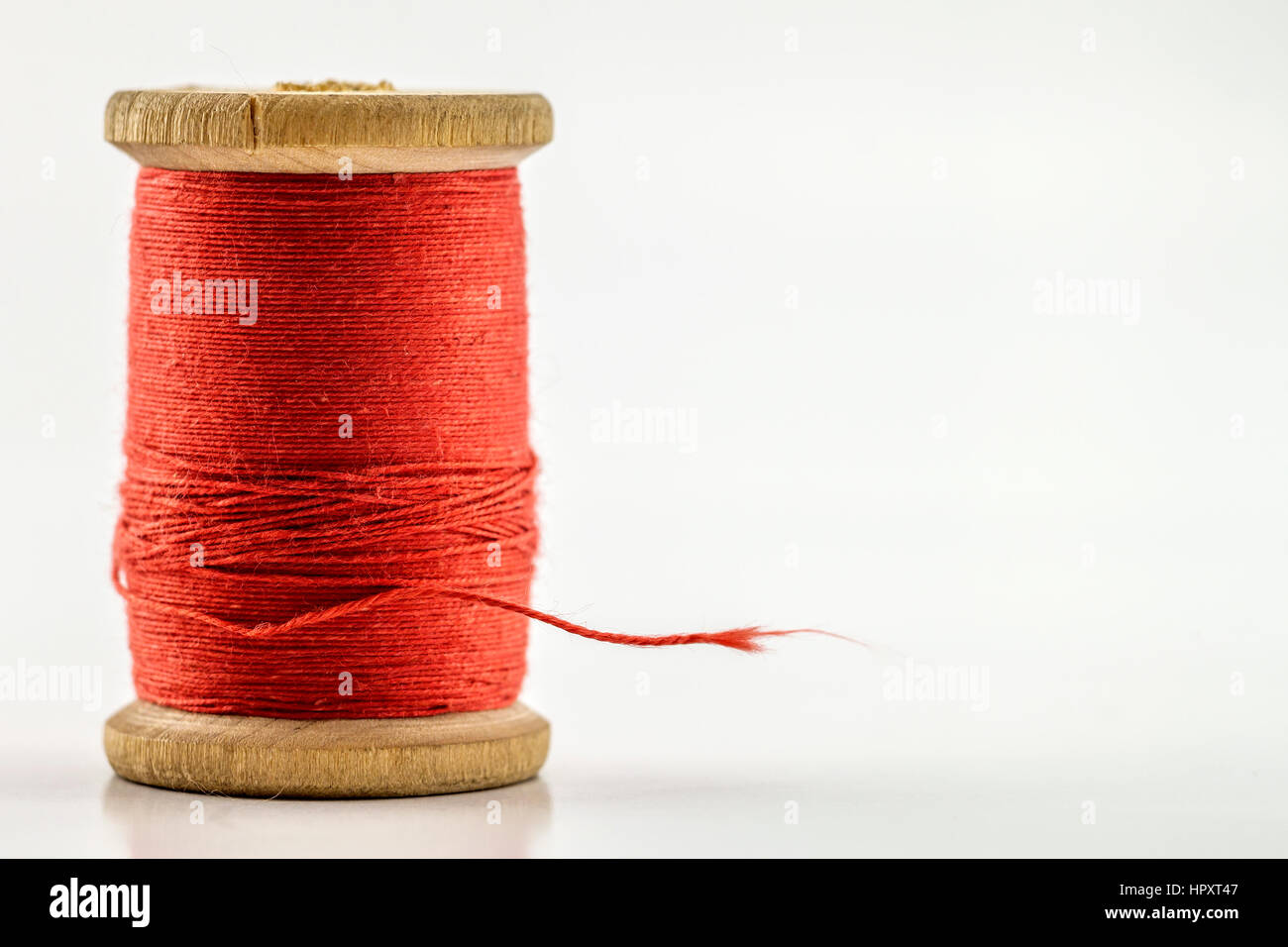 Reel or spool of red sewing thread isolated on white. Shallow depth of ...