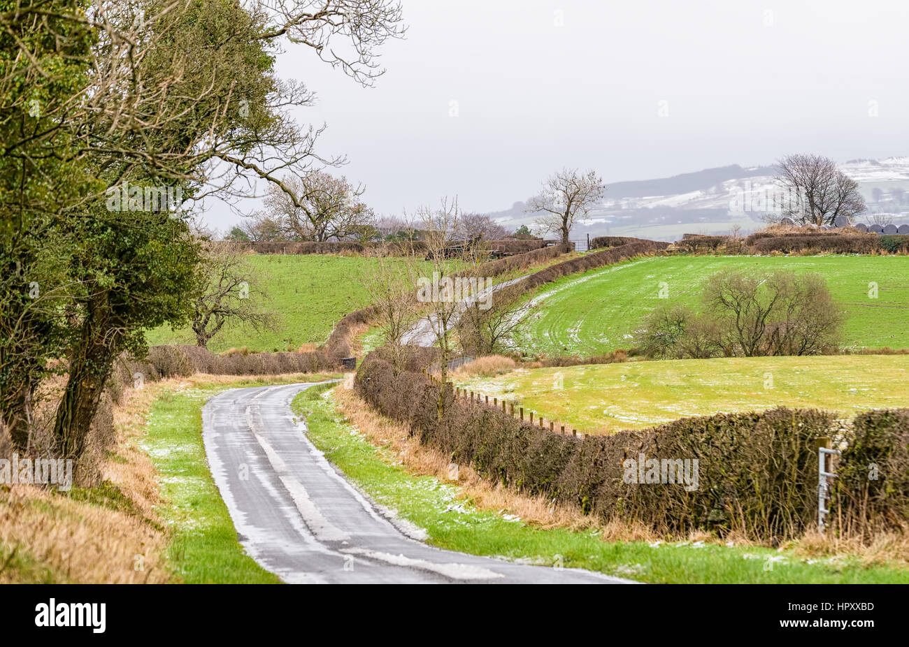 Icy Road with lightly covered snowie hills in the far distance. The ...