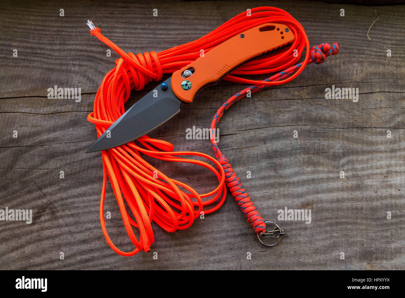 Pocket knife with an orange handle. View from above. Parachute cord ...
