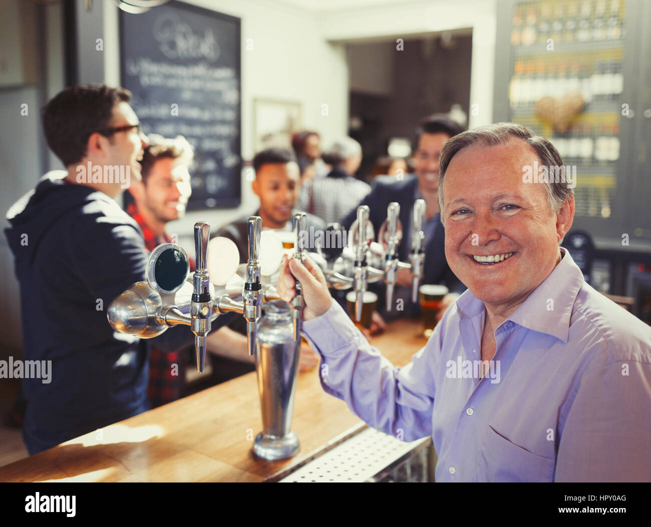 Portrait smiling male bartender standing at tap behind bar Stock Photo ...