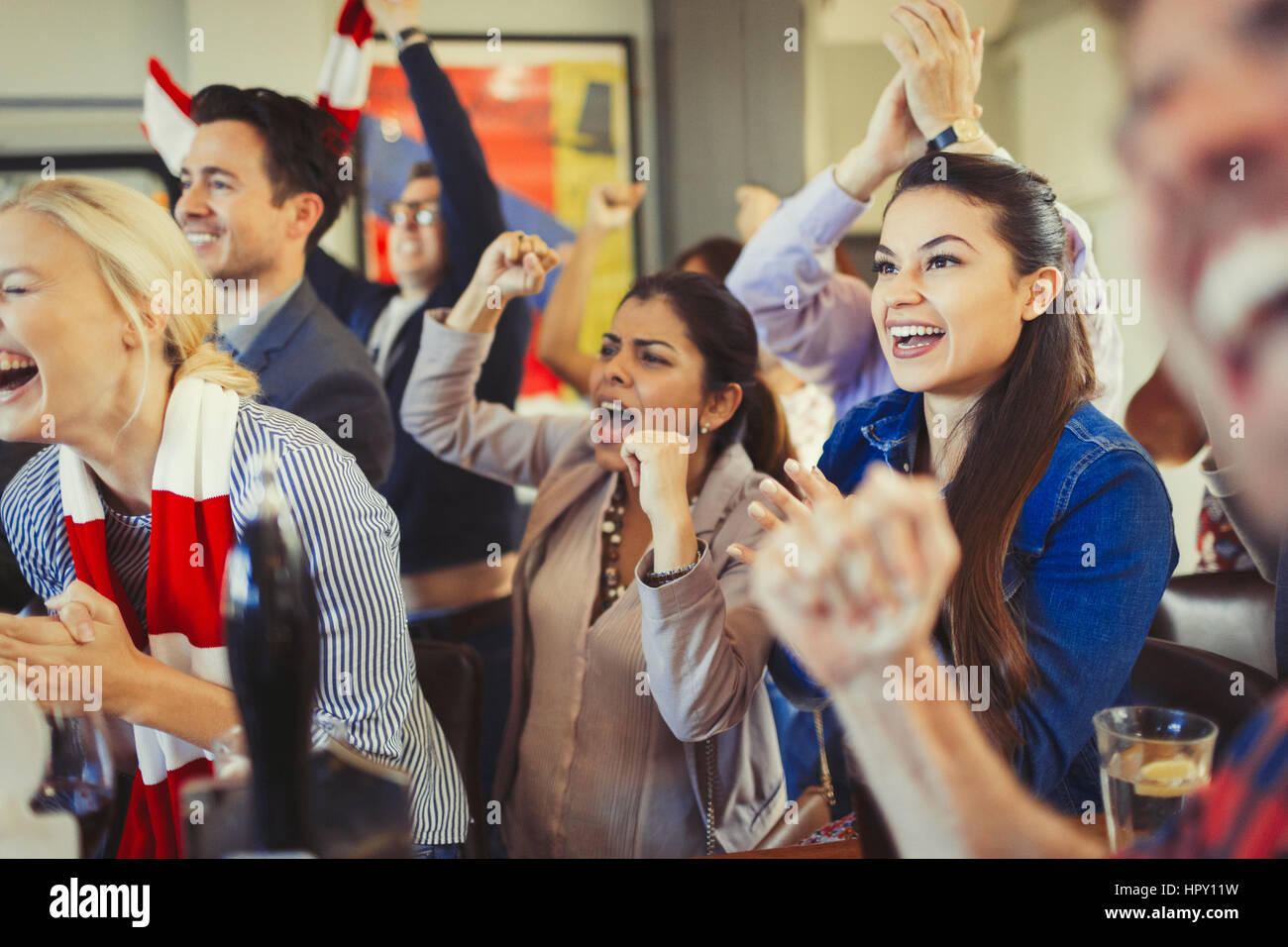 Enthusiastic sports fans cheering watching game at bar Stock Photo - Alamy