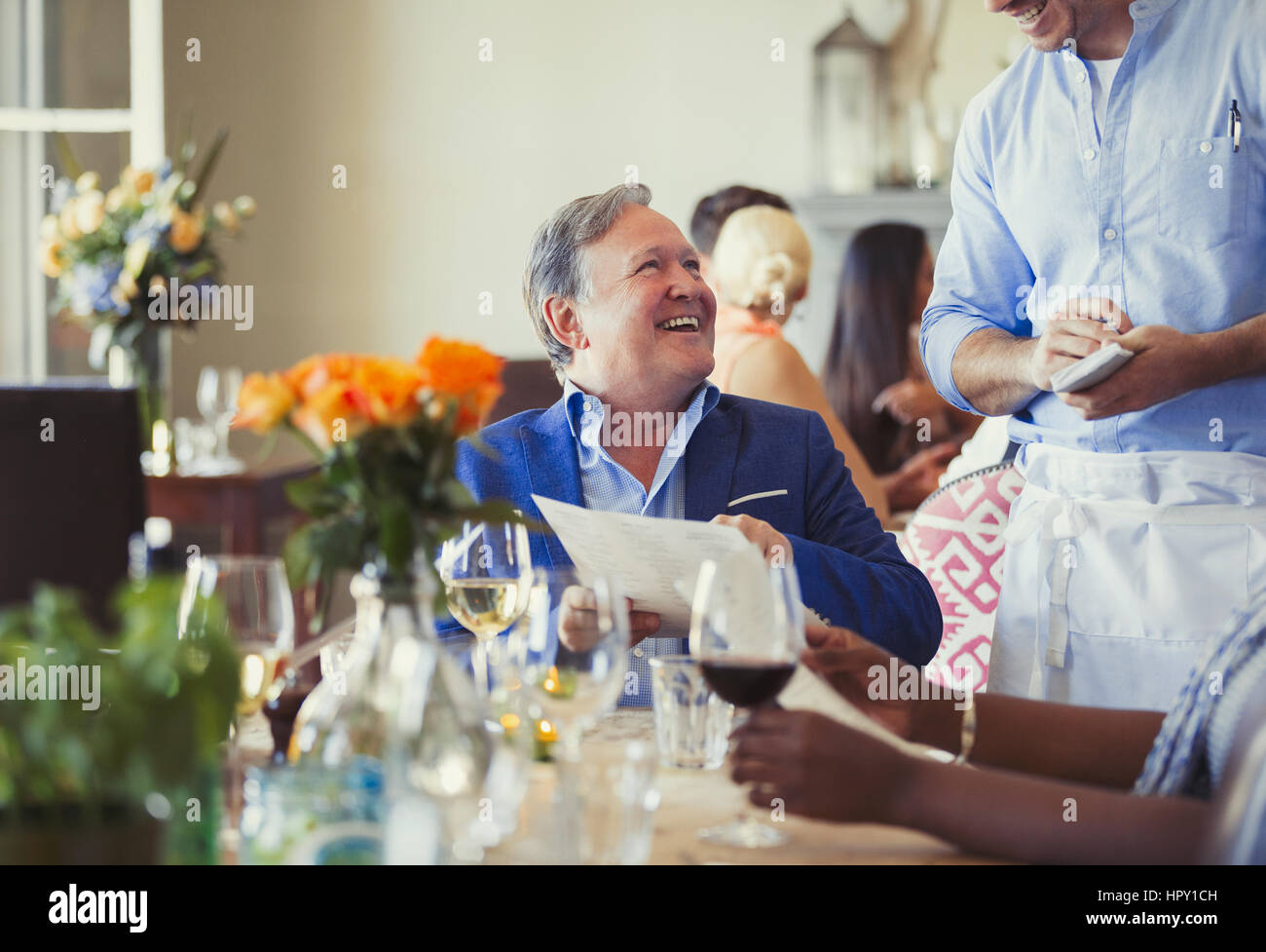 Smiling man with menu ordering from waiter at restaurant table Stock ...