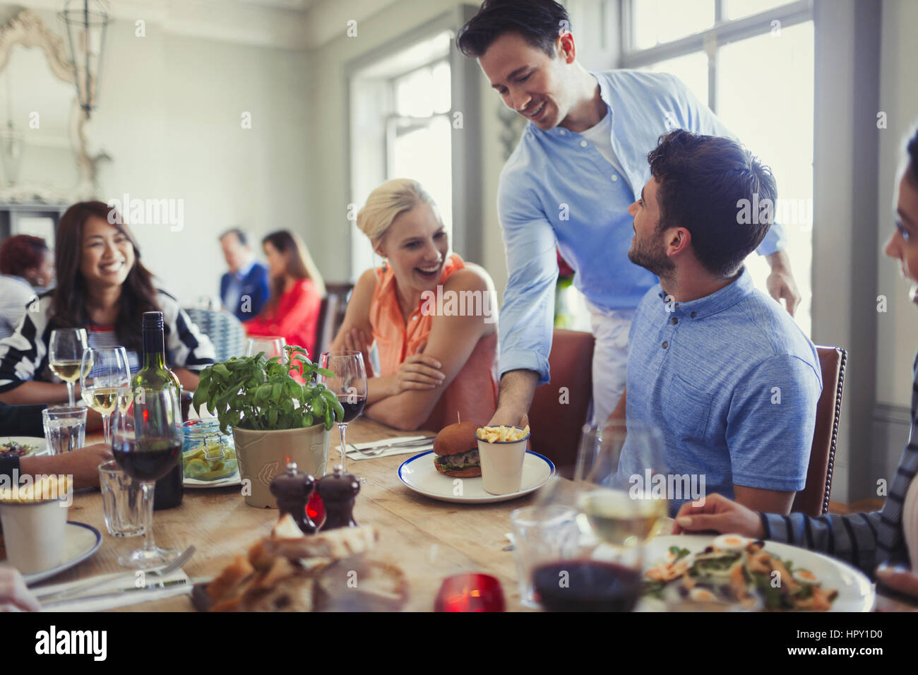Waiter serving food to friends dining at restaurant table Stock Photo ...