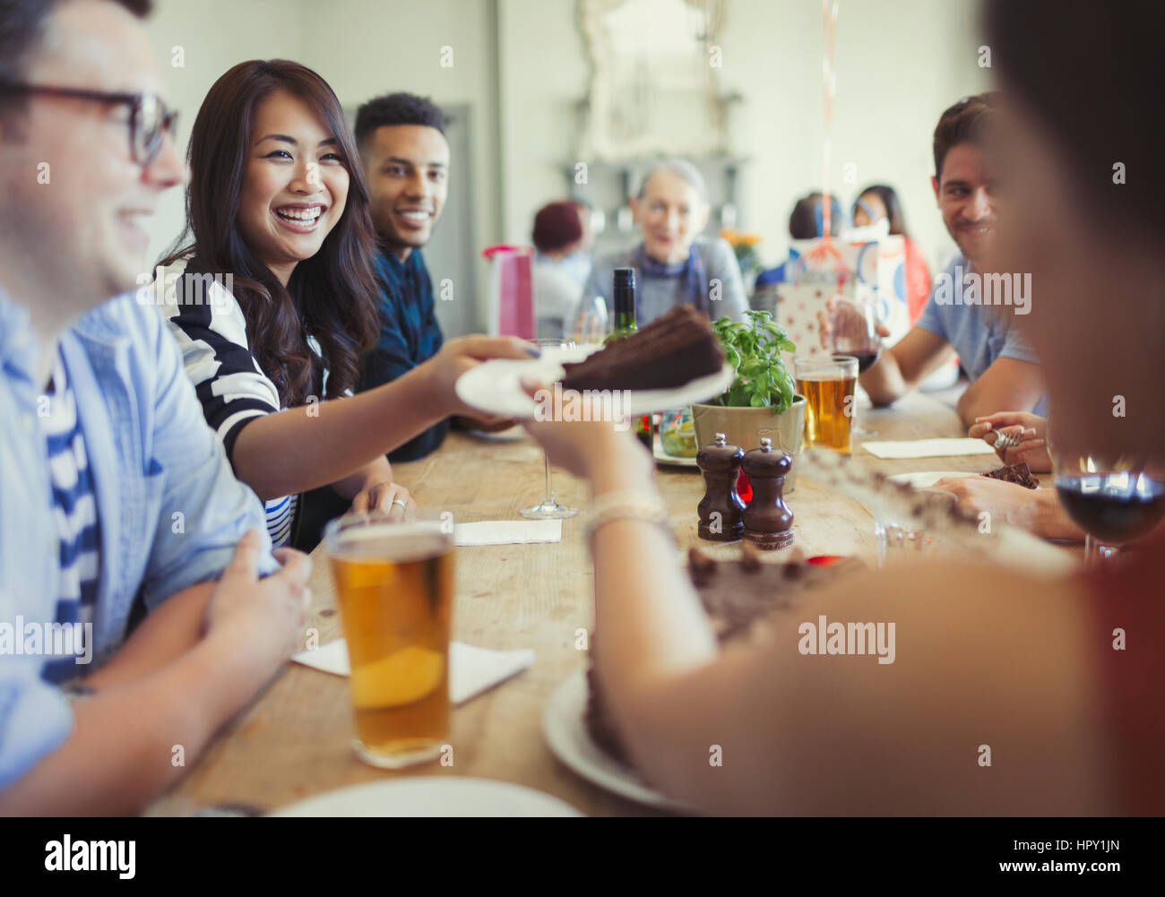 Woman serving chocolate birthday cake to friend at restaurant table ...