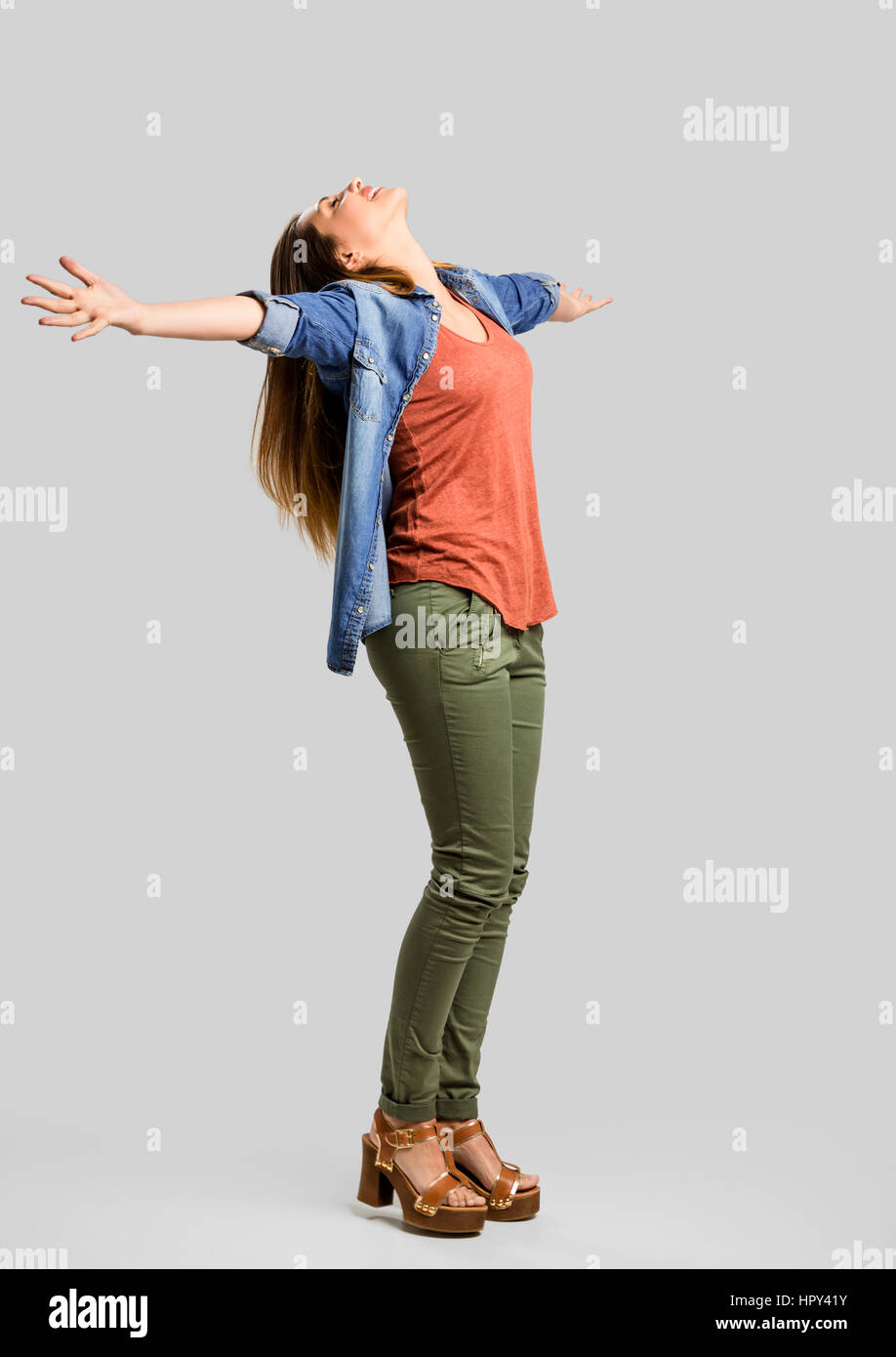 Beautiful happy woman with arms up over a gray background Stock Photo ...