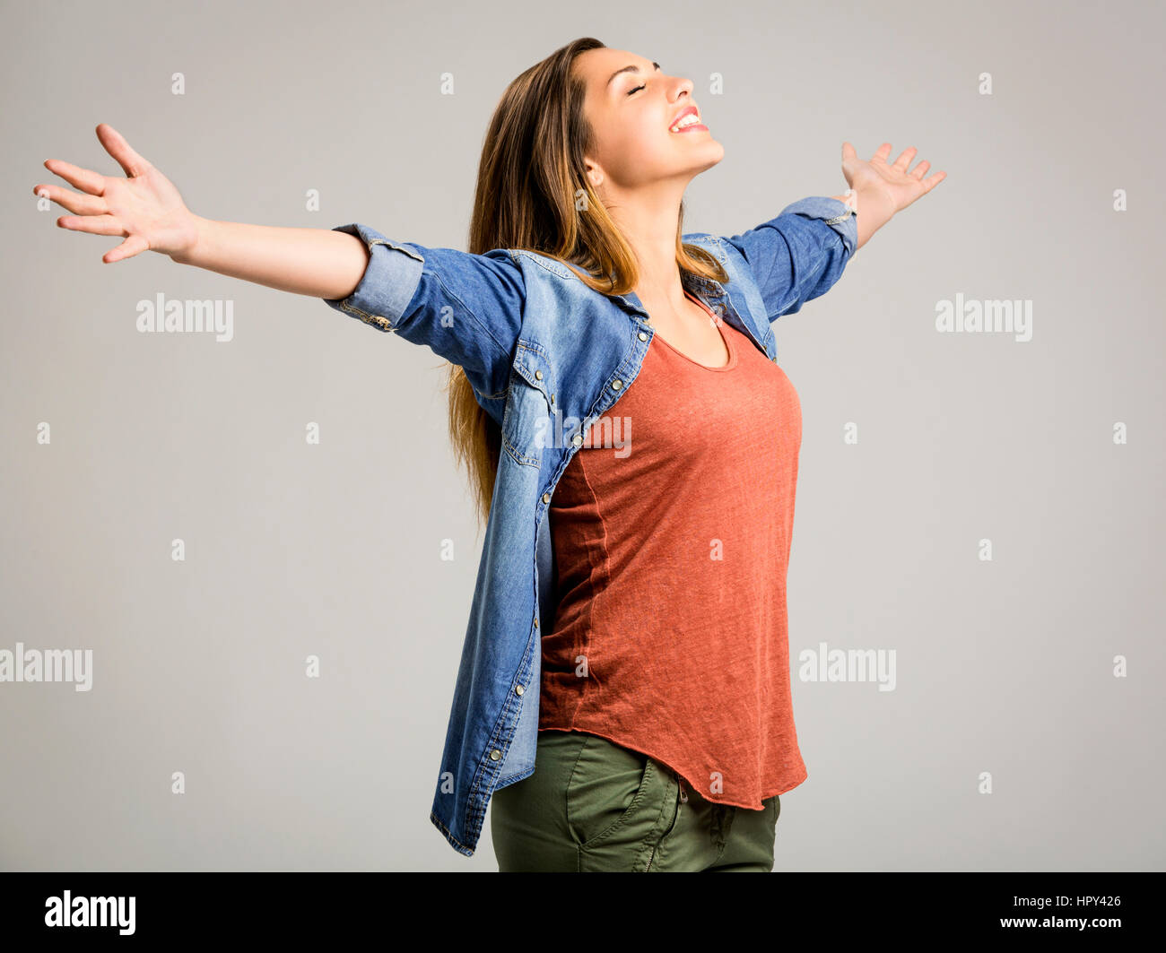 Beautiful happy woman with arms up over a gray background Stock Photo ...