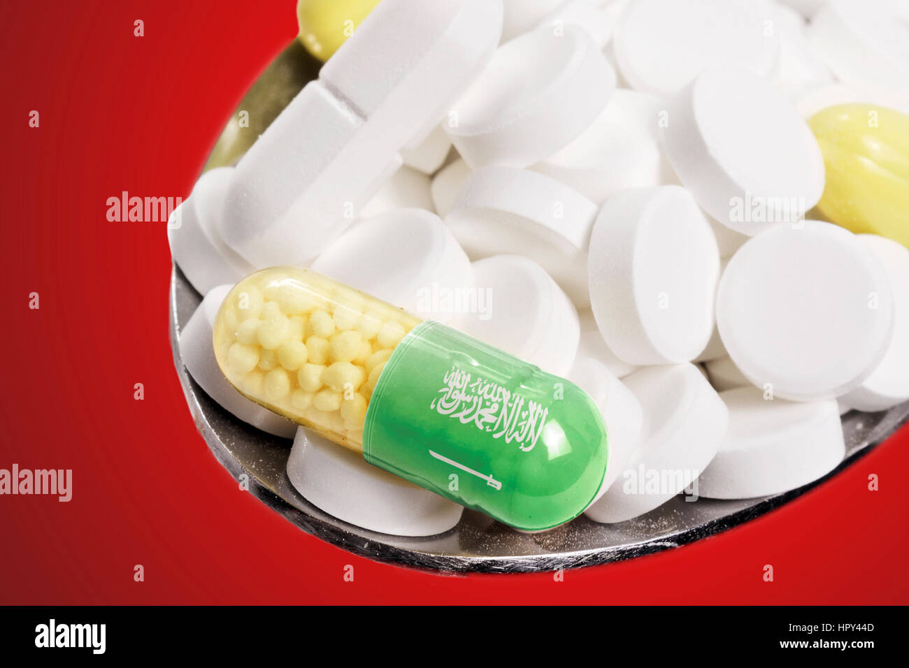 The national flag of Saudi Arabia on a capsule and pills on a spoon ...