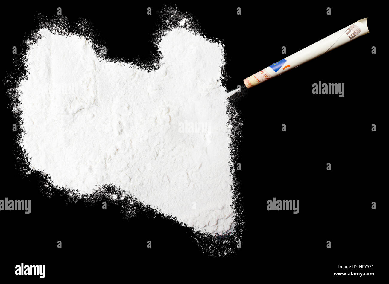 A powder drug like cocaine in the shape of Libya with a rolled money ...