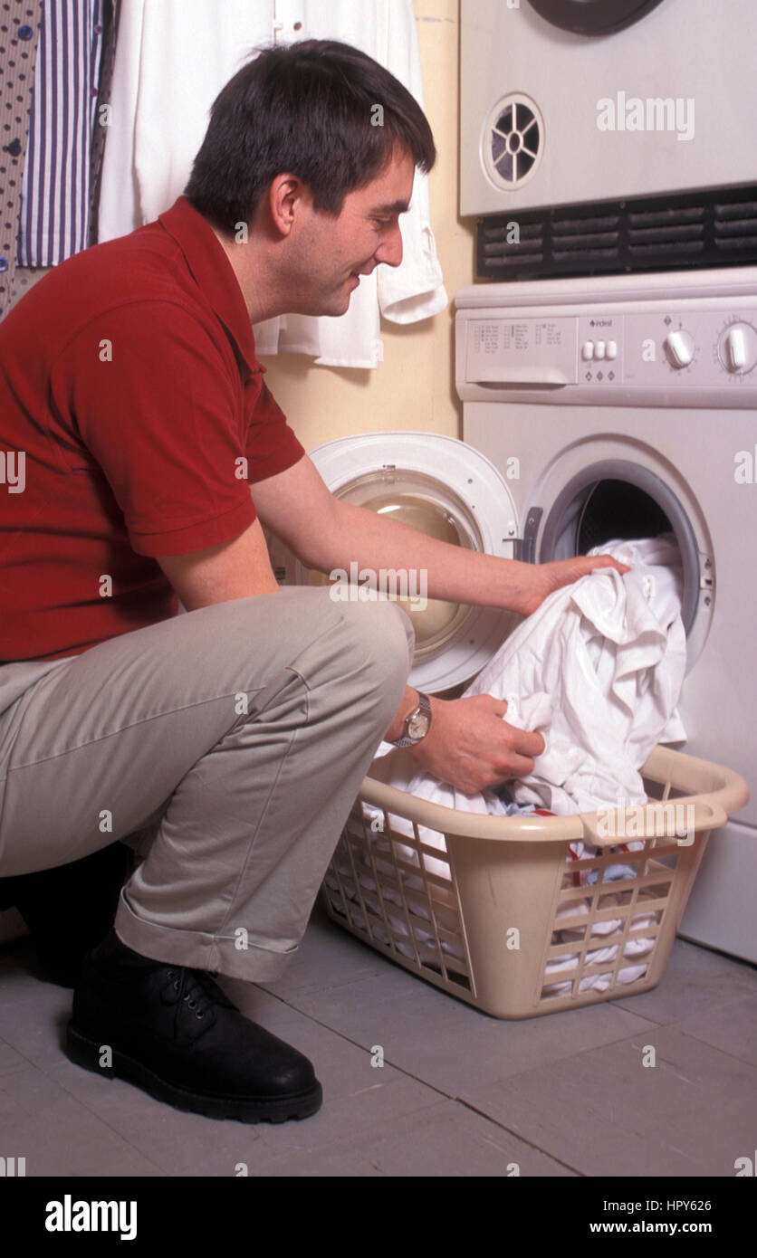 man putting laundry into washing machine Stock Photo - Alamy