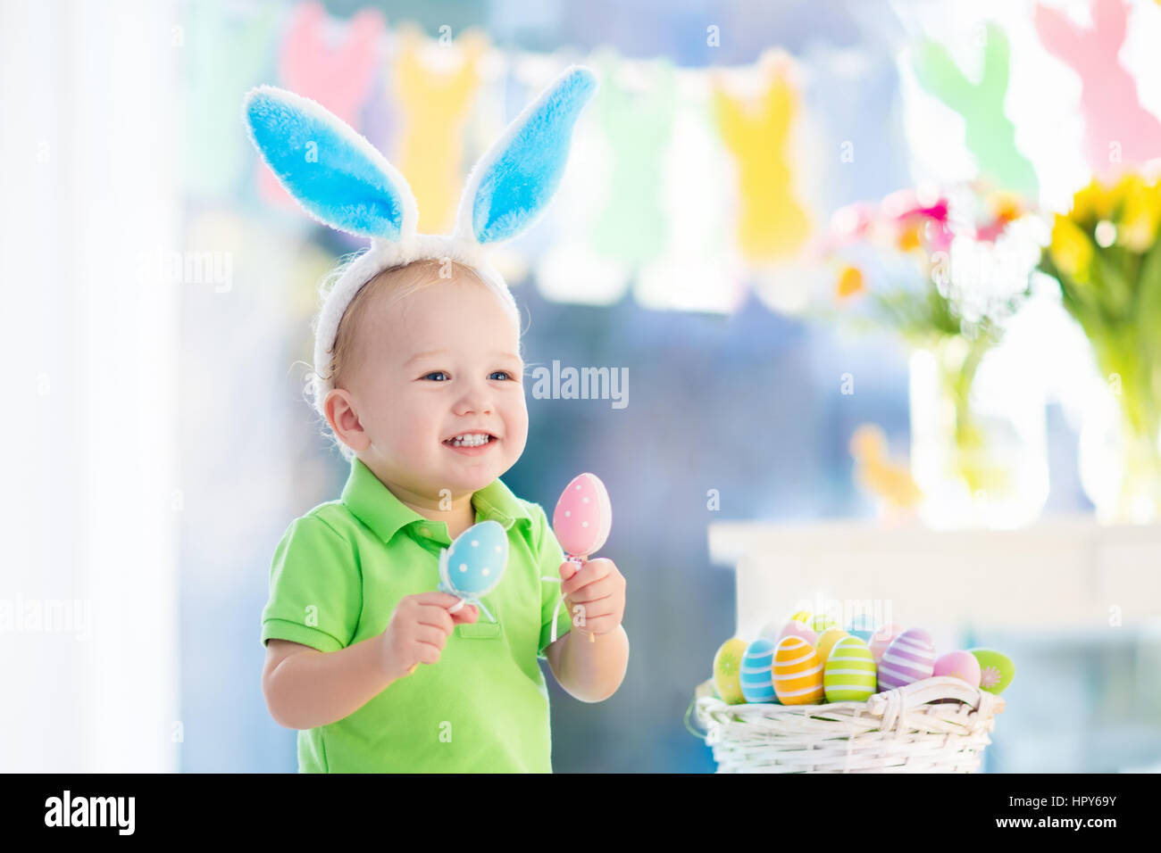 Kids celebrate Easter. Funny happy baby in bunny ears playing with ...