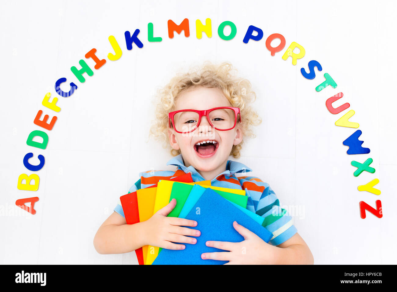 Happy preschool child learning to read and write playing with colorful ...