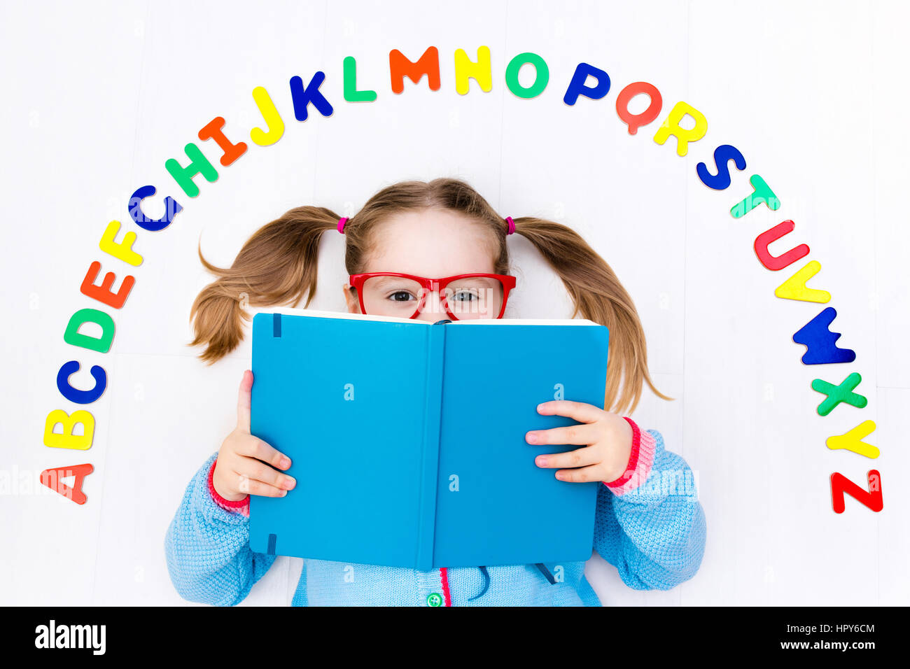 Happy preschool child learning to read and write playing with colorful ...