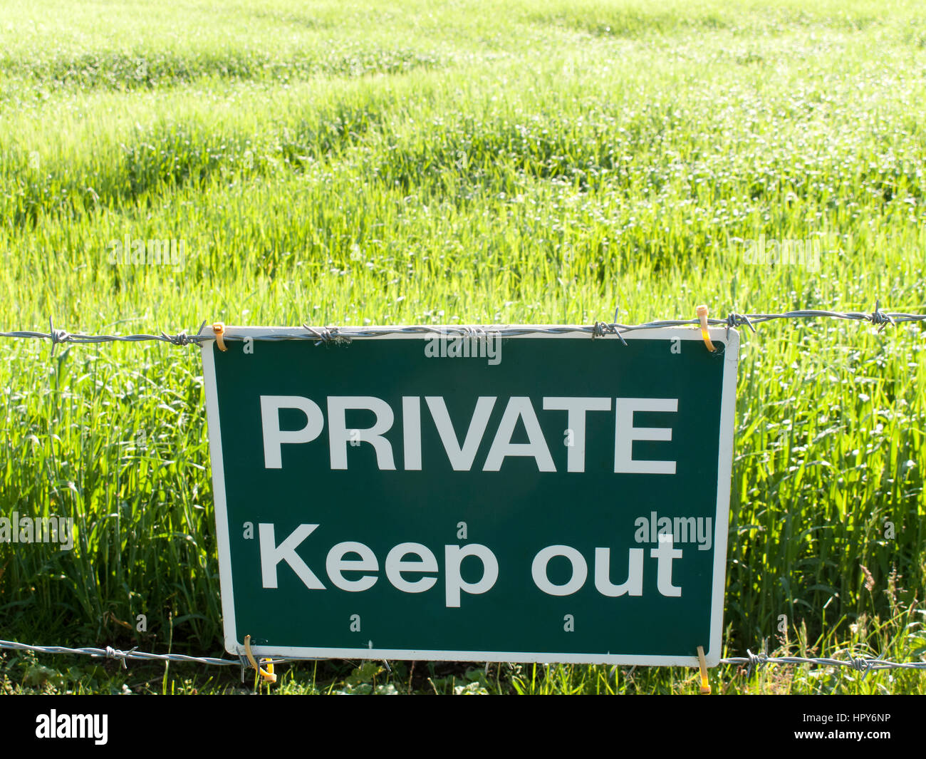 Private keep out sign on barbed wire boundary fence to farmland Stock ...