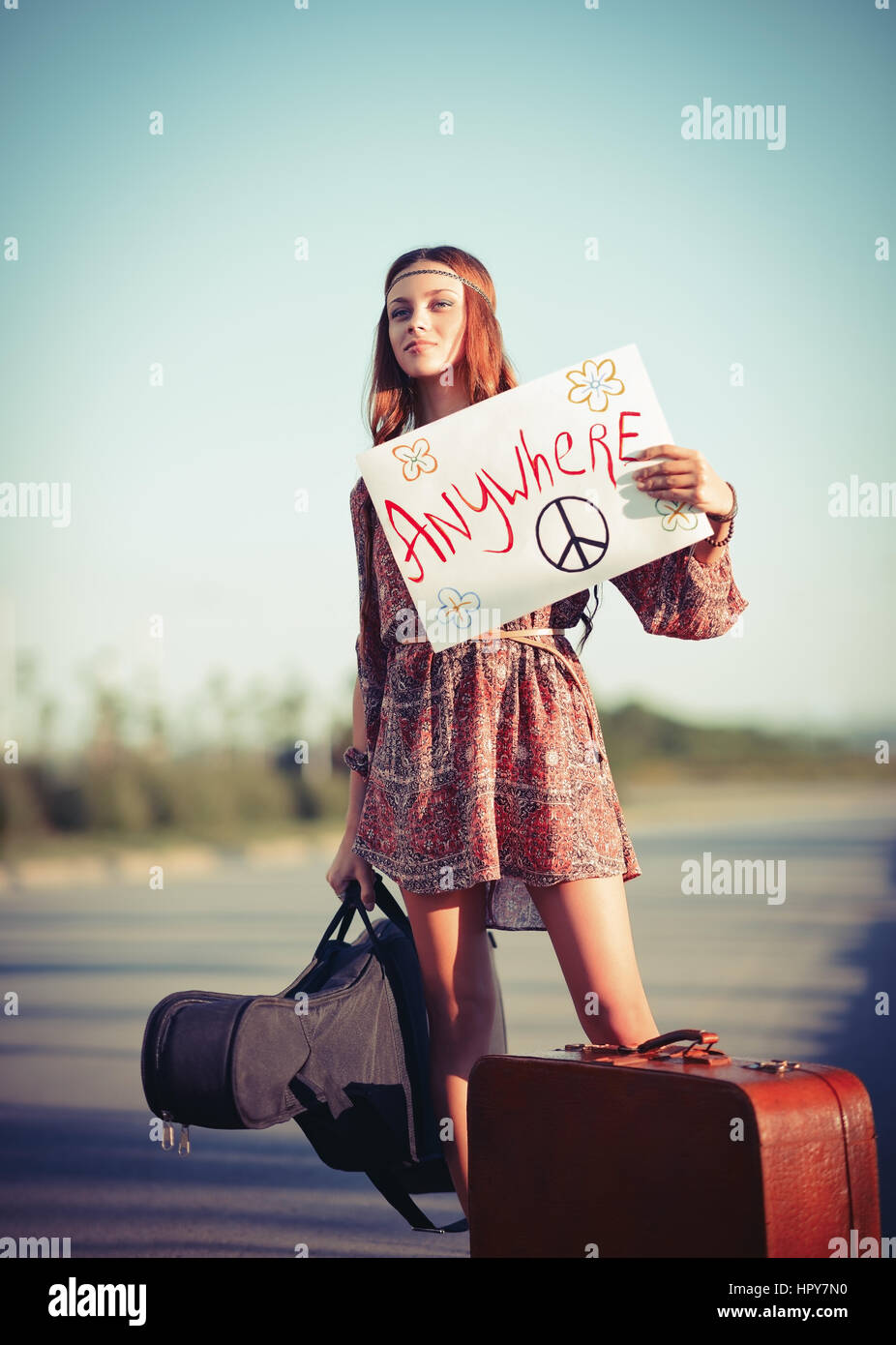 Beautiful young hippie girl hitchhiking on the road. Sunset time Stock ...