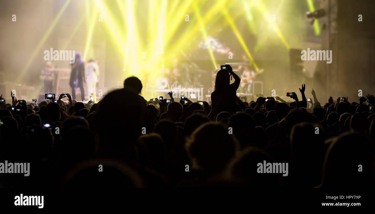 Photo of many people enjoying rock concert, crowd with raised up hands ...