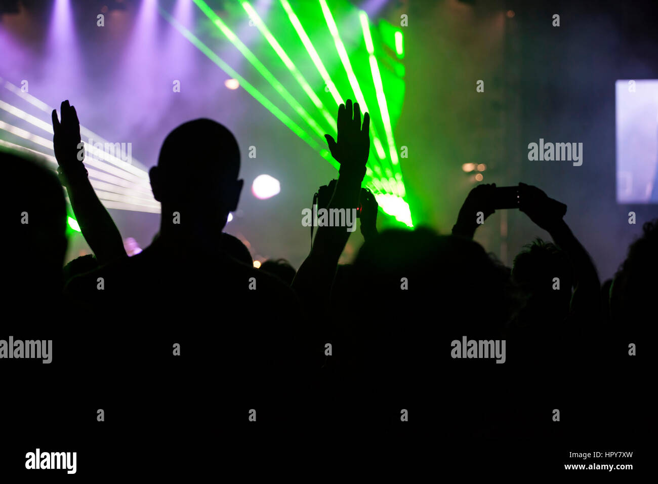 Photo of many people enjoying rock concert, crowd with raised up hands ...