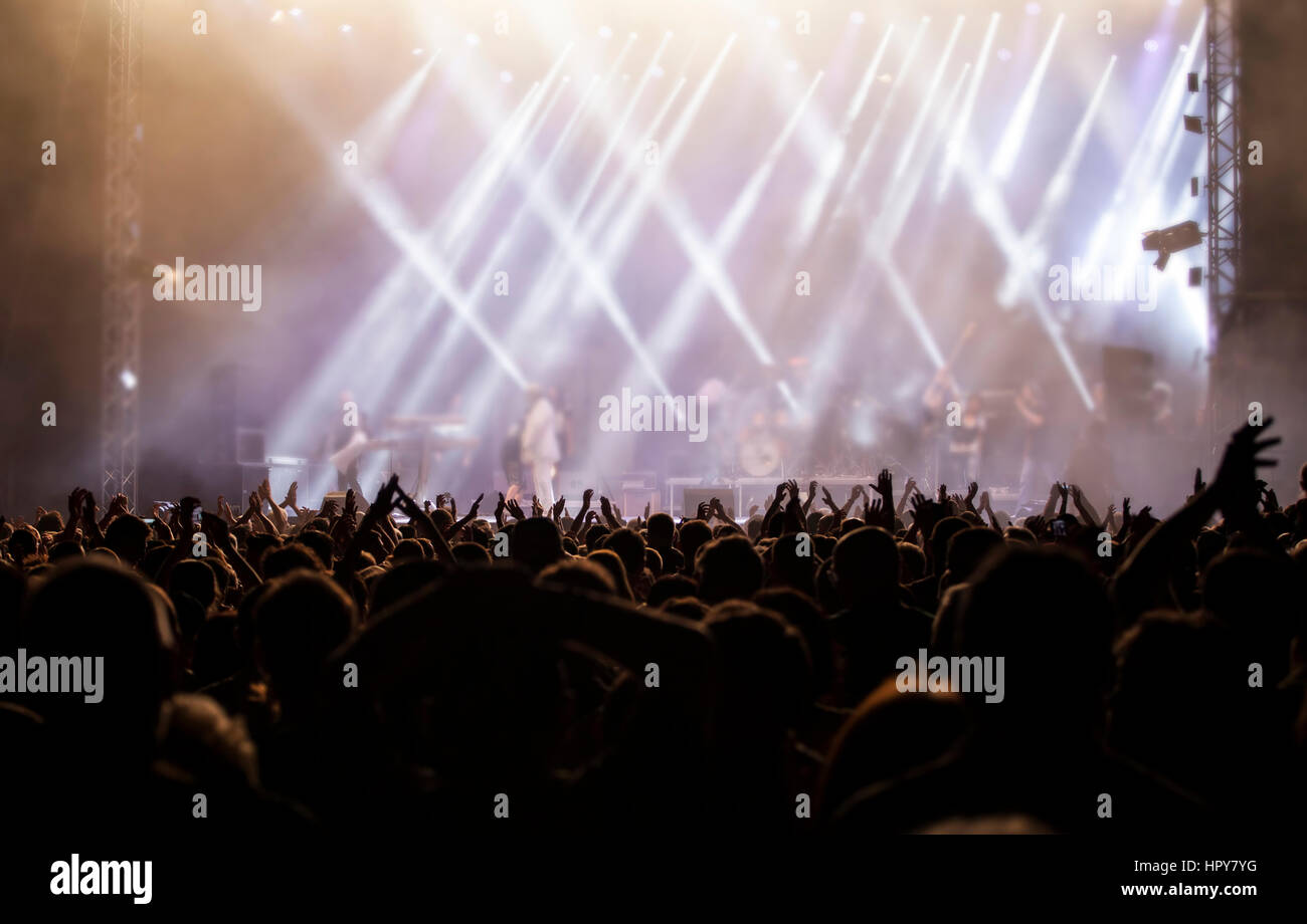 Photo of many people enjoying rock concert, crowd with raised up hands ...