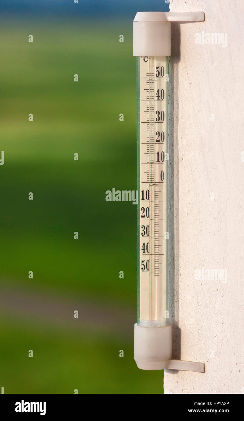 Thermometer celsius showing warm temperature on blurred green ...