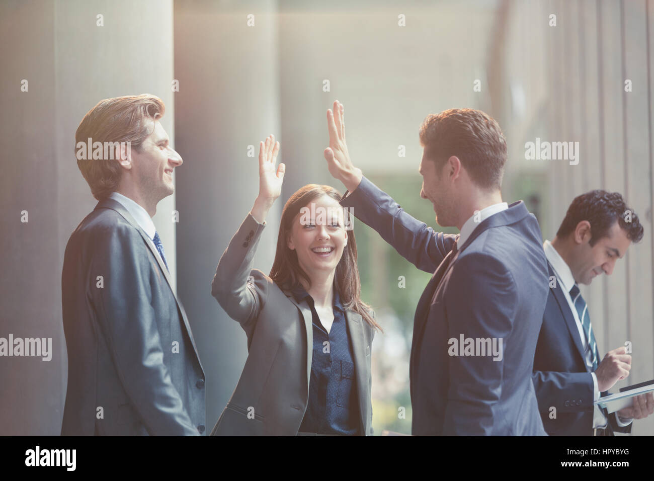 Business people high-fiving in office lobby Stock Photo - Alamy