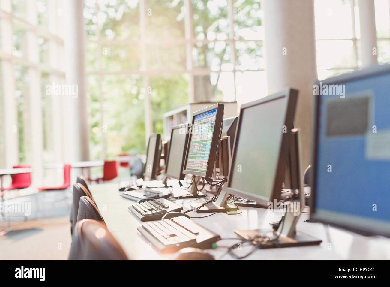 Computers in a row in sunny library office Stock Photo - Alamy