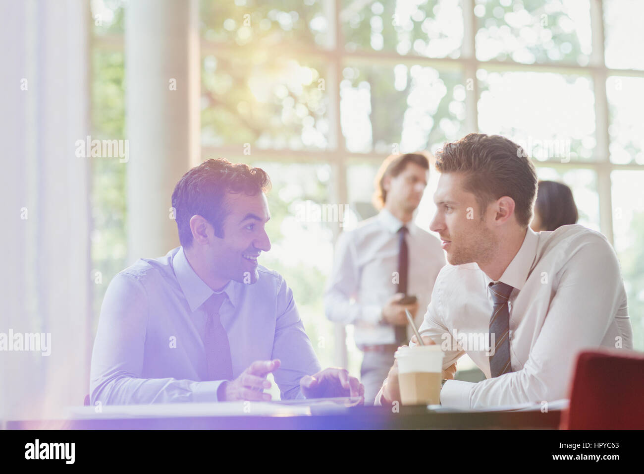 Businessmen drinking coffee and talking in office meeting Stock Photo ...