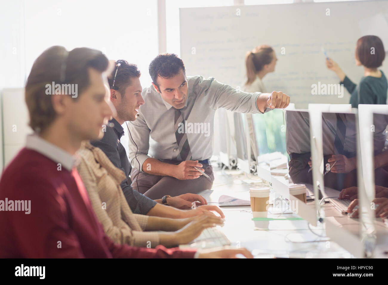 Male supervisor talking with telemarketer at computer in office Stock ...
