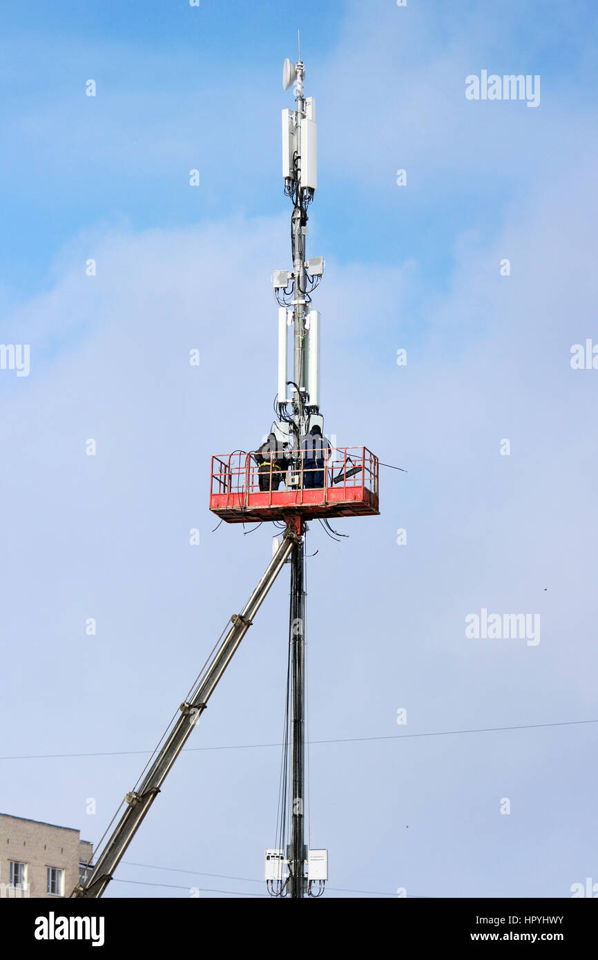 Two workers assemble equipment for telecommunications on the tower with ...