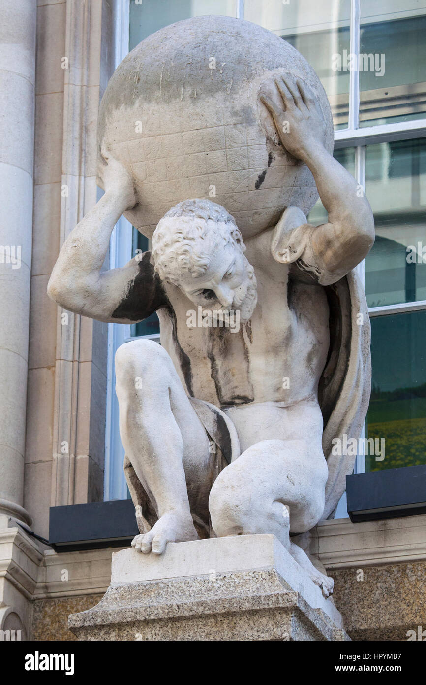 A sculpture of a man carrying a sphere on his back, on the facade of a ...