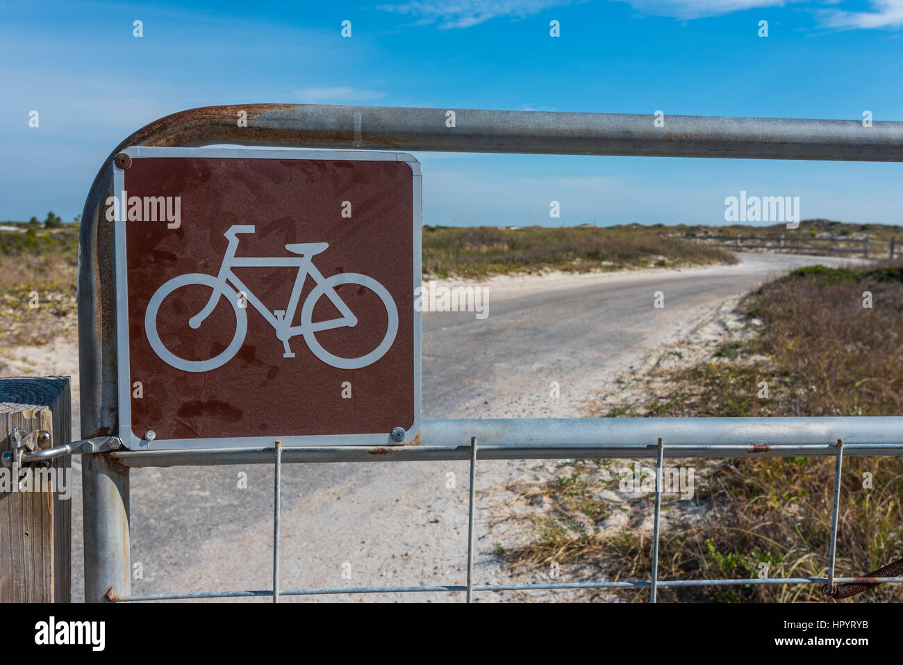 Bicycle Sign on Metal Gate in front of sandy dirt road Stock Photo - Alamy