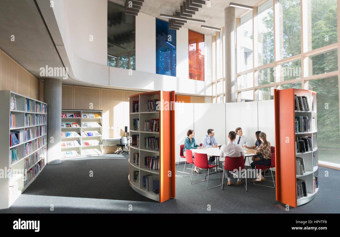 Business people meeting at round table in open plan library Stock Photo ...
