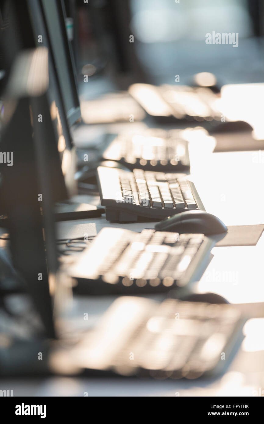 Computers and computer keyboards in a row in sunny office Stock Photo ...