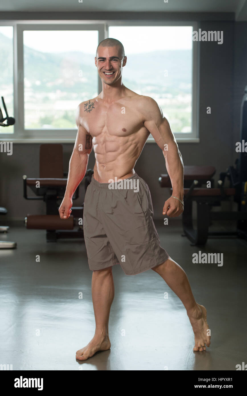 Young Man Standing Strong In The Gym And Flexing Muscles - Muscular ...
