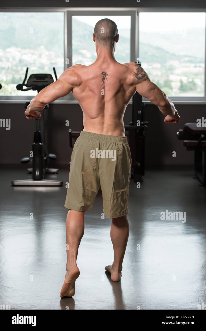 Young Man Standing Strong In The Gym And Flexing Muscles - Muscular ...