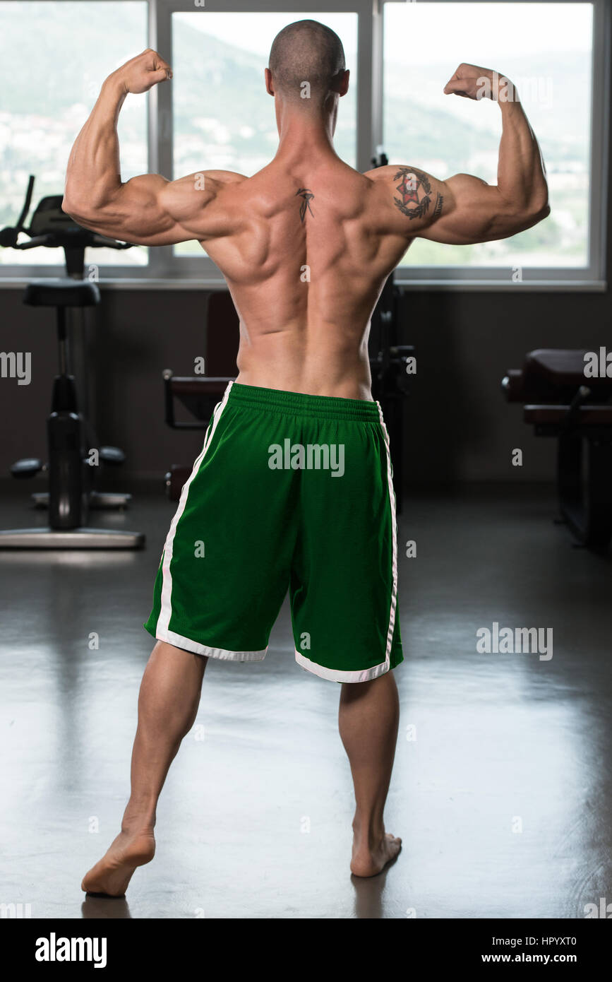 Young Man Standing Strong In The Gym And Flexing Muscles - Muscular ...