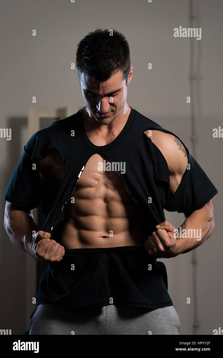 Handsome Man Standing Strong In The Gym And Ripping the T-Shirt Off ...