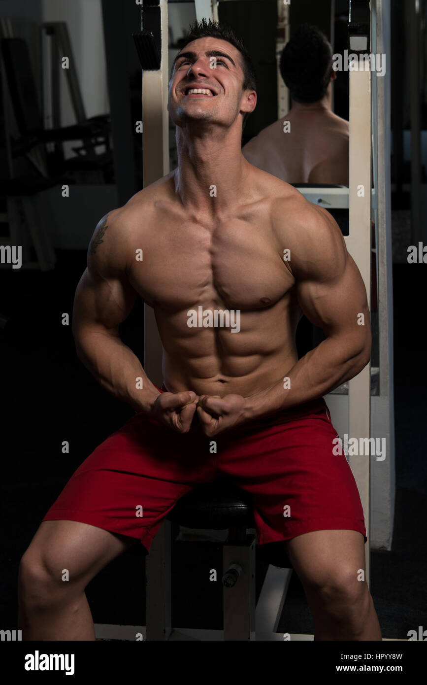 Handsome Man Sitting Strong In The Gym And Flexing Muscles - Muscular ...