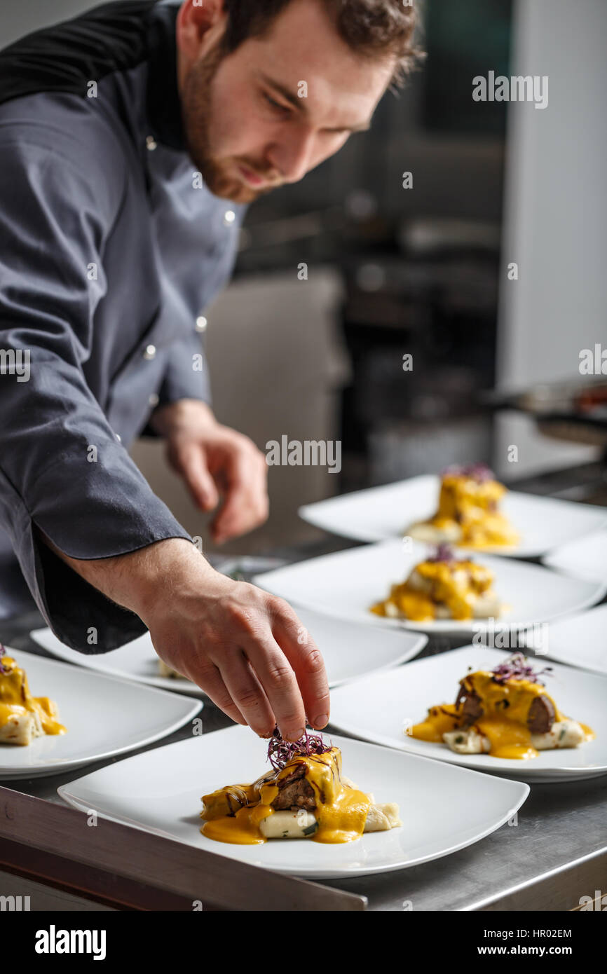 Young chef prepares delicious meals in restaurant kitchen Stock Photo ...