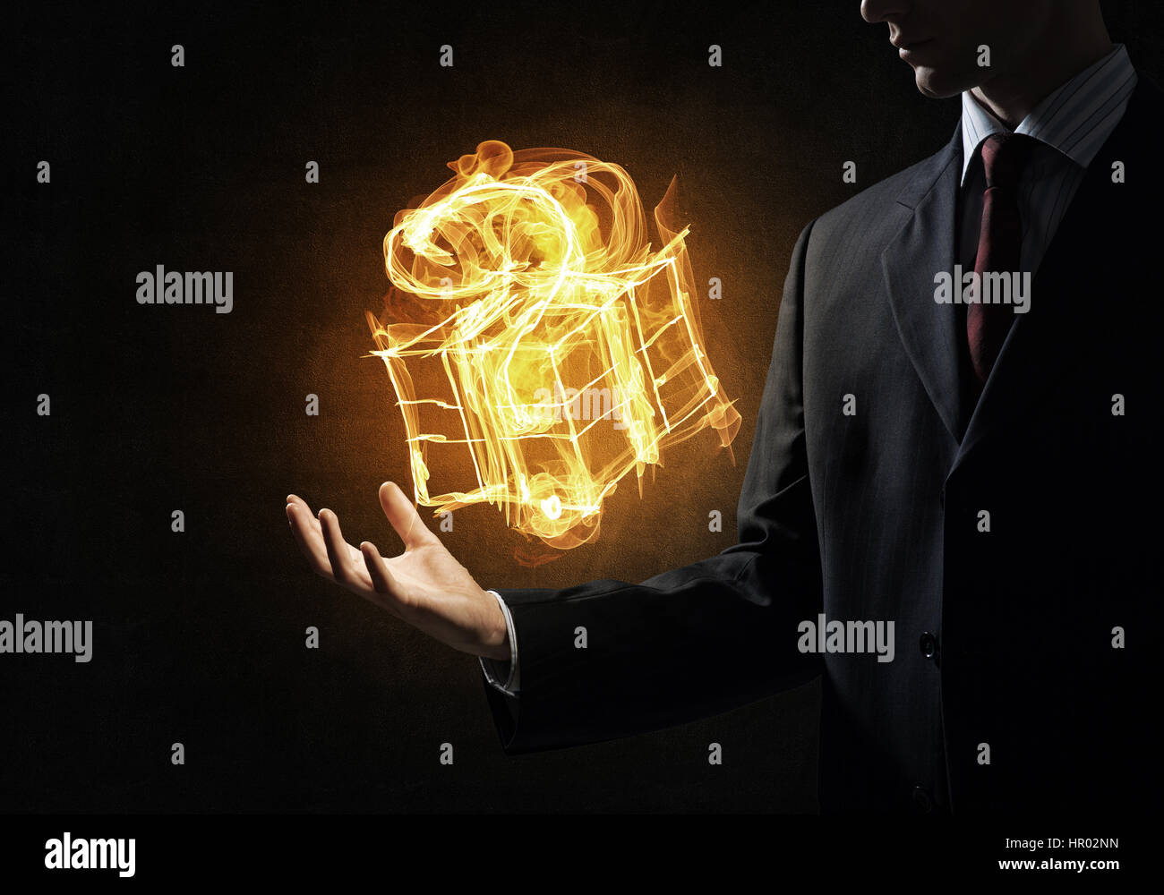 Glowing fire gift box icon in palm on dark background Stock Photo - Alamy
