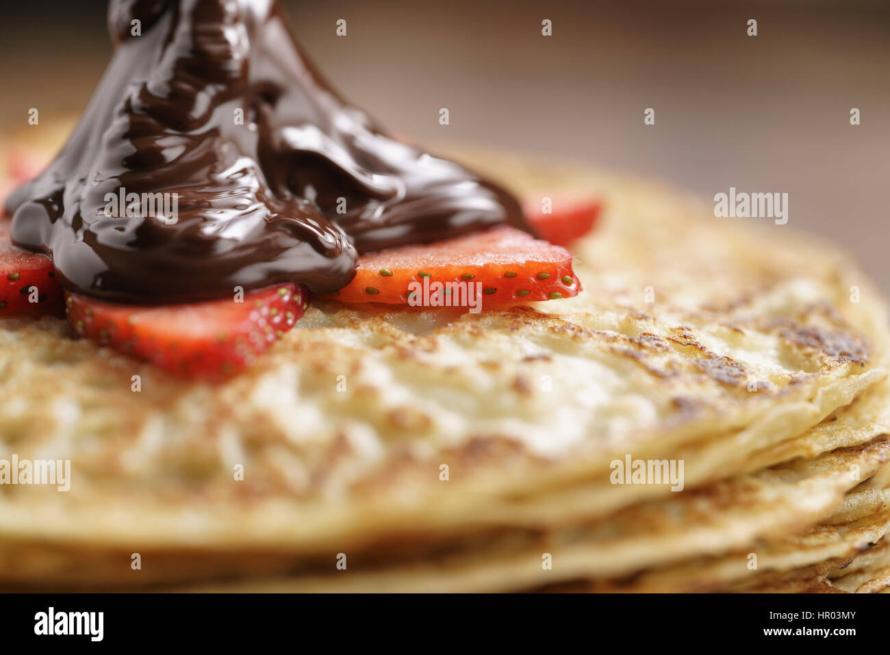 premium dark chocolate poured on blinis with strawberry, shallow focus ...