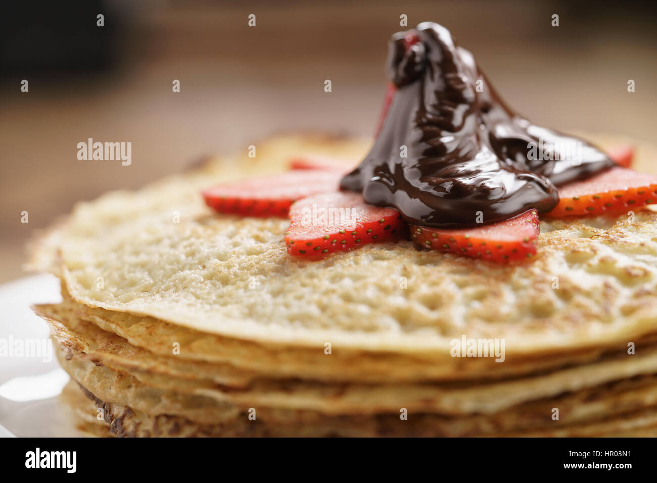 premium dark chocolate poured on blinis with strawberry, shallow focus ...