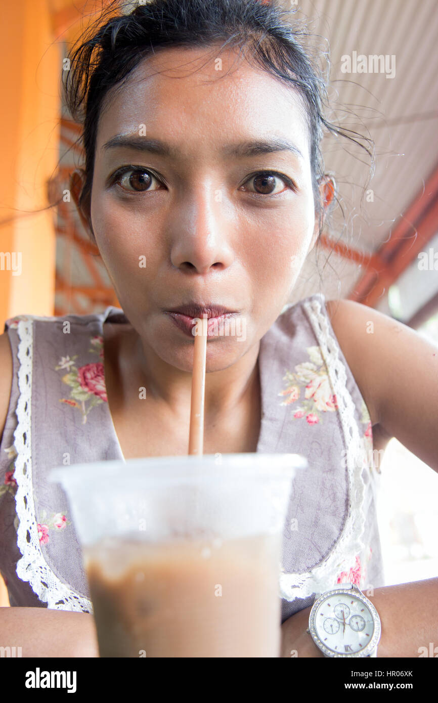 Portrait of a girl drinking iced coffee in a outdoors restaurant ...