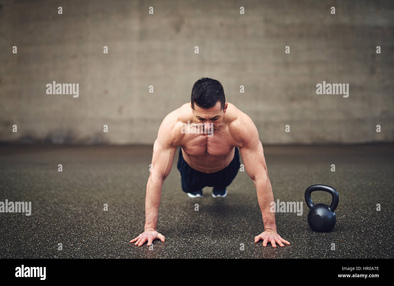 Front view of young shirtless muscular man doing push-ups with ...