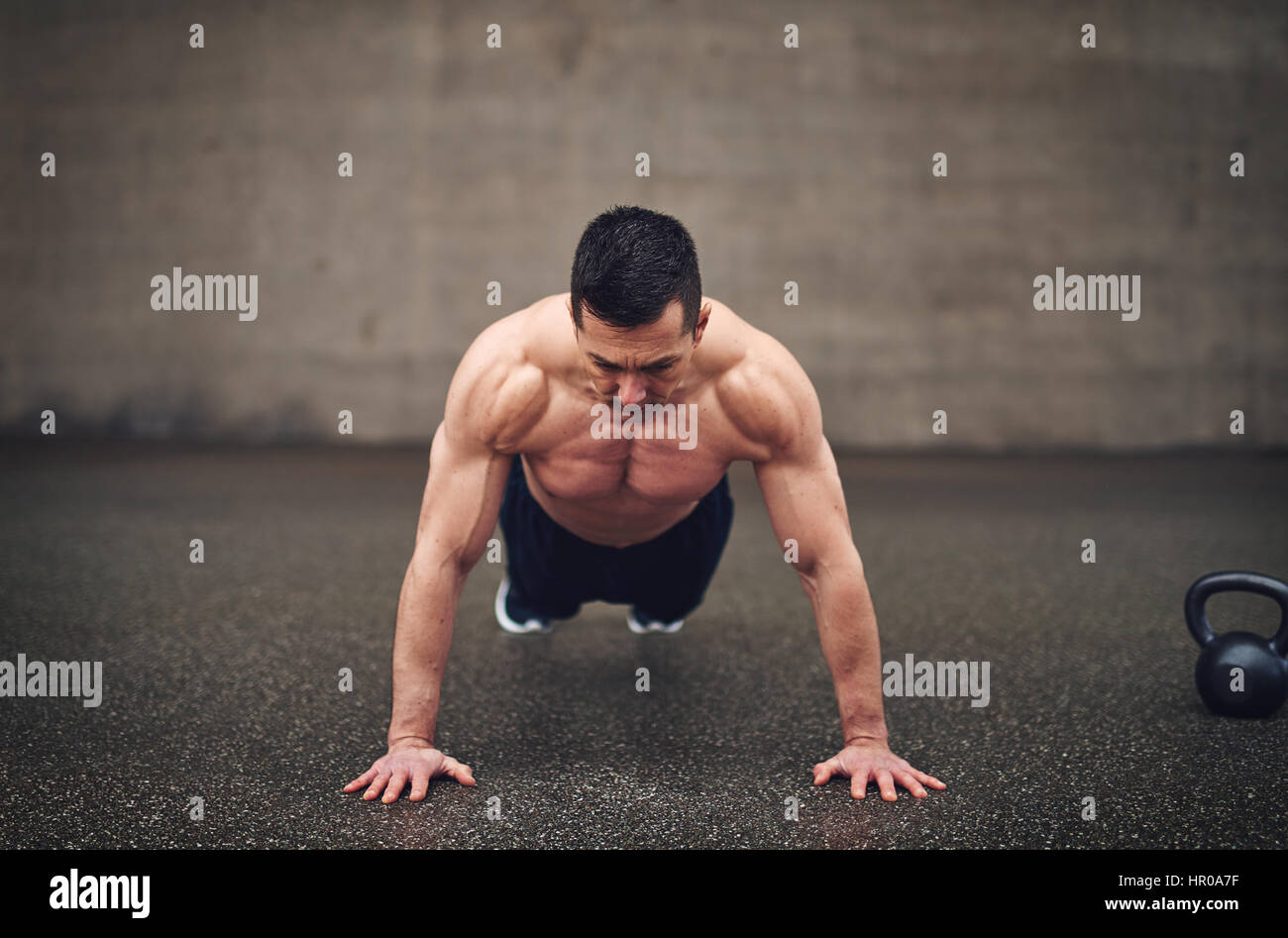 Front view of young sportive male doing push-ups on blurred background ...
