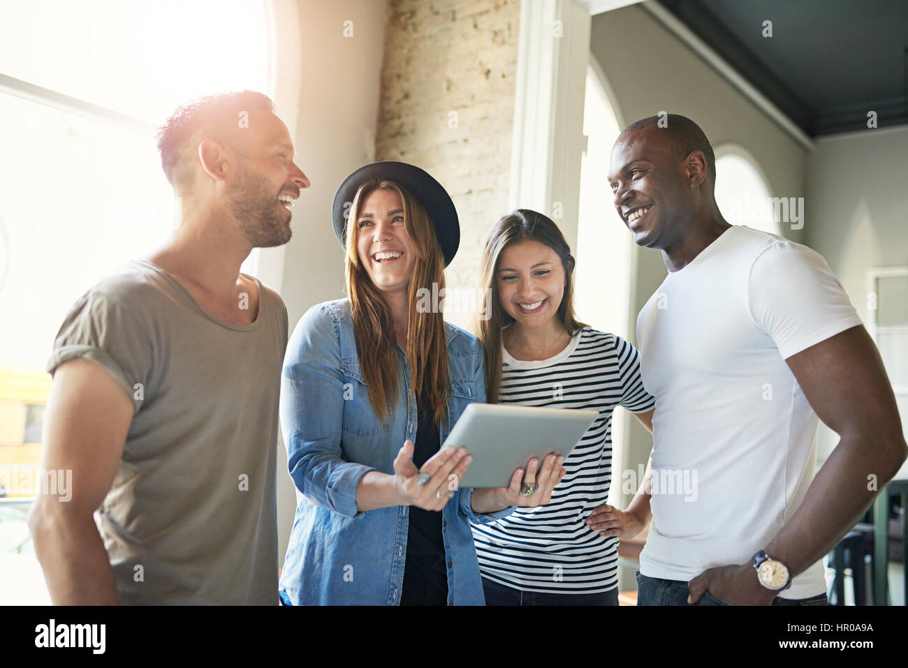 Four young trendy people standing and having cheerful conversation ...